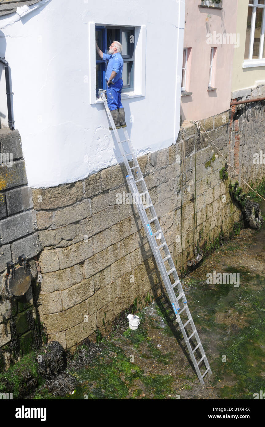 A painter on a ladder in a harbor as the tide comes in Stock Photo - Alamy
