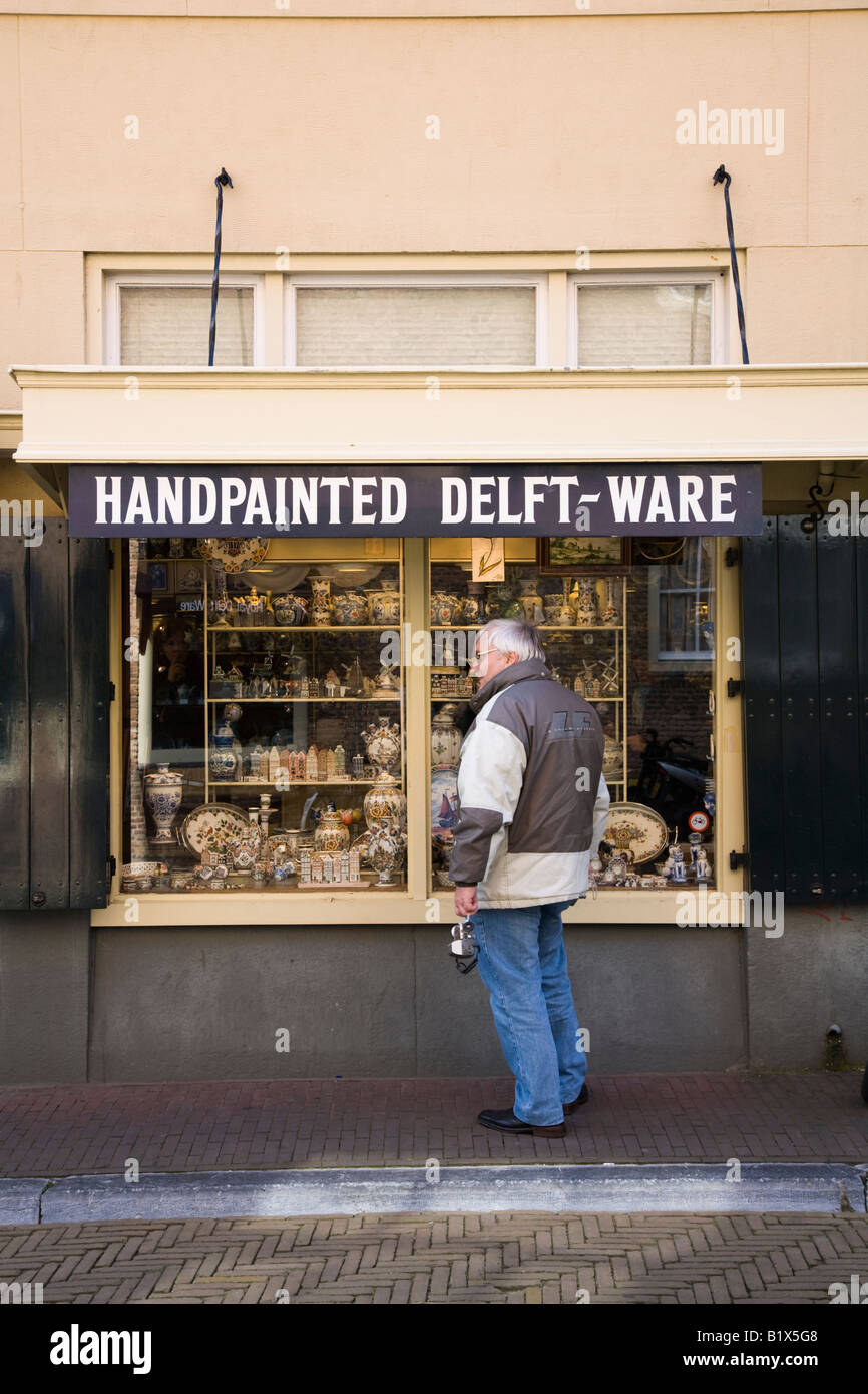 Passer by looks at Royal Delftware pottery on display in a shop window ...