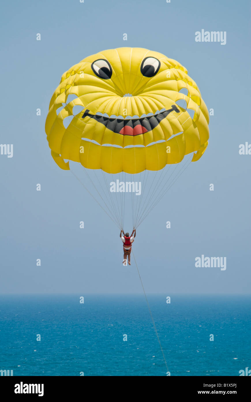 Vertical view of a couple harnessed together in midair on a parasailing ride with a bright ...