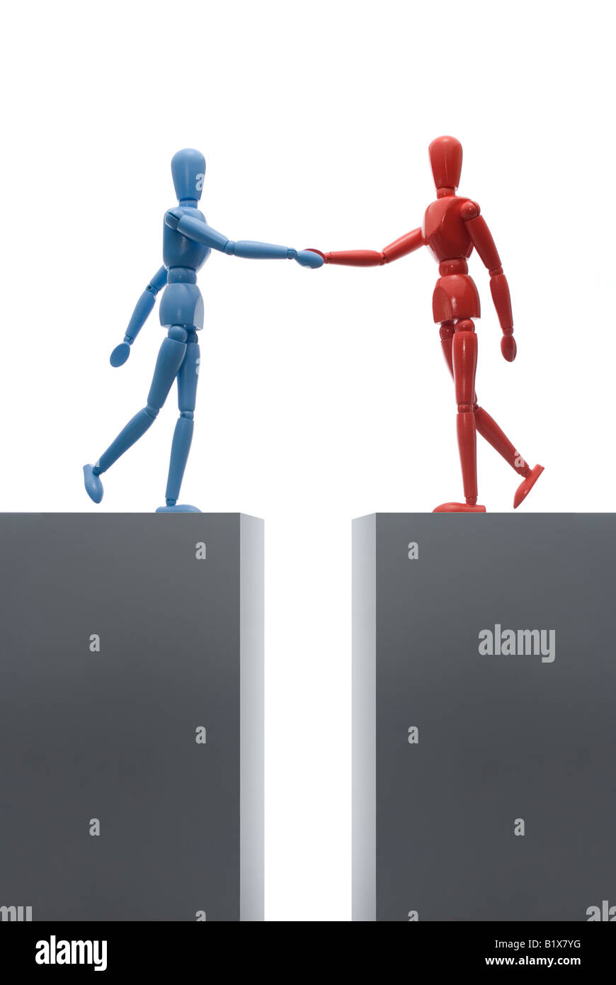 Two human mannequin figures shake hands across a gap Stock Photo - Alamy