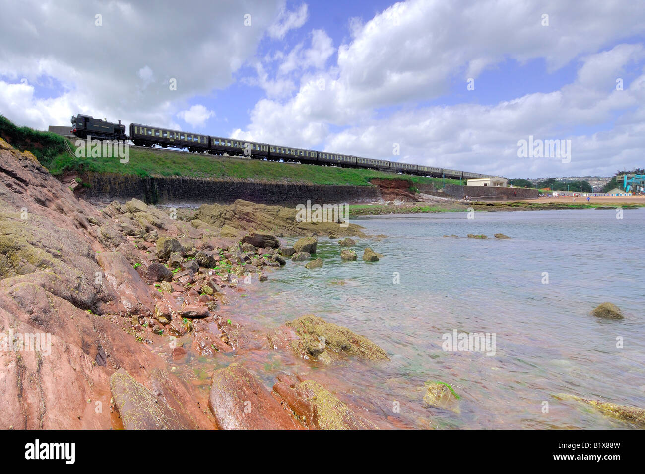 A steam train on the Paignton to Dartmouth line passing the rocky ...