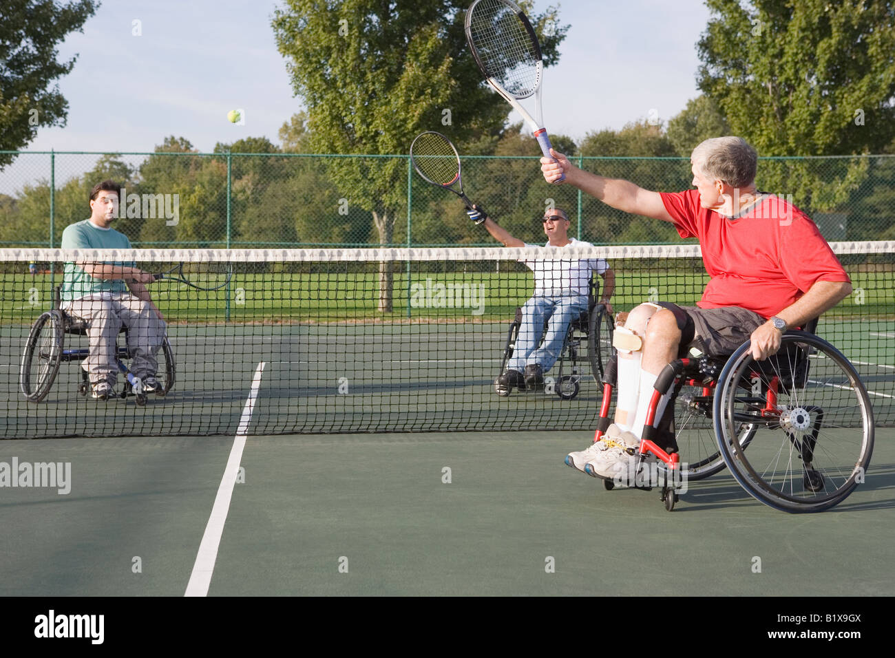 Two senior men and a mid adult man playing tennis Stock Photo - Alamy