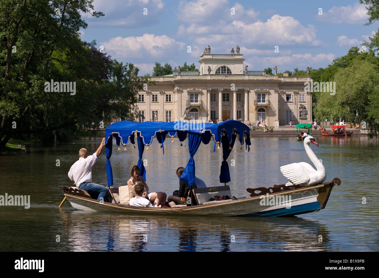People relax in a gondola with Lazienkowski Palace in background ...