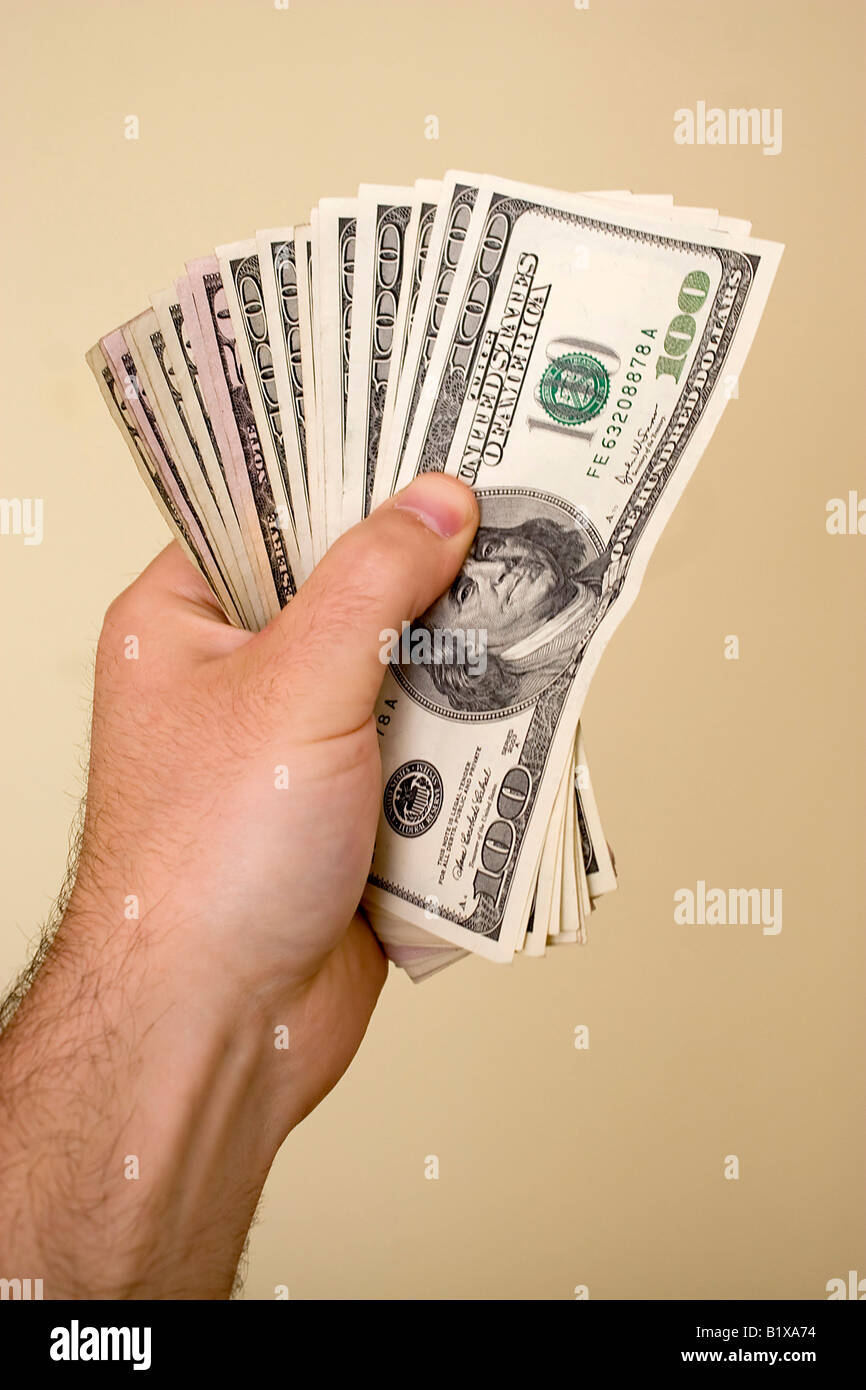 A handful of cash isolated over a gold background Stock Photo - Alamy