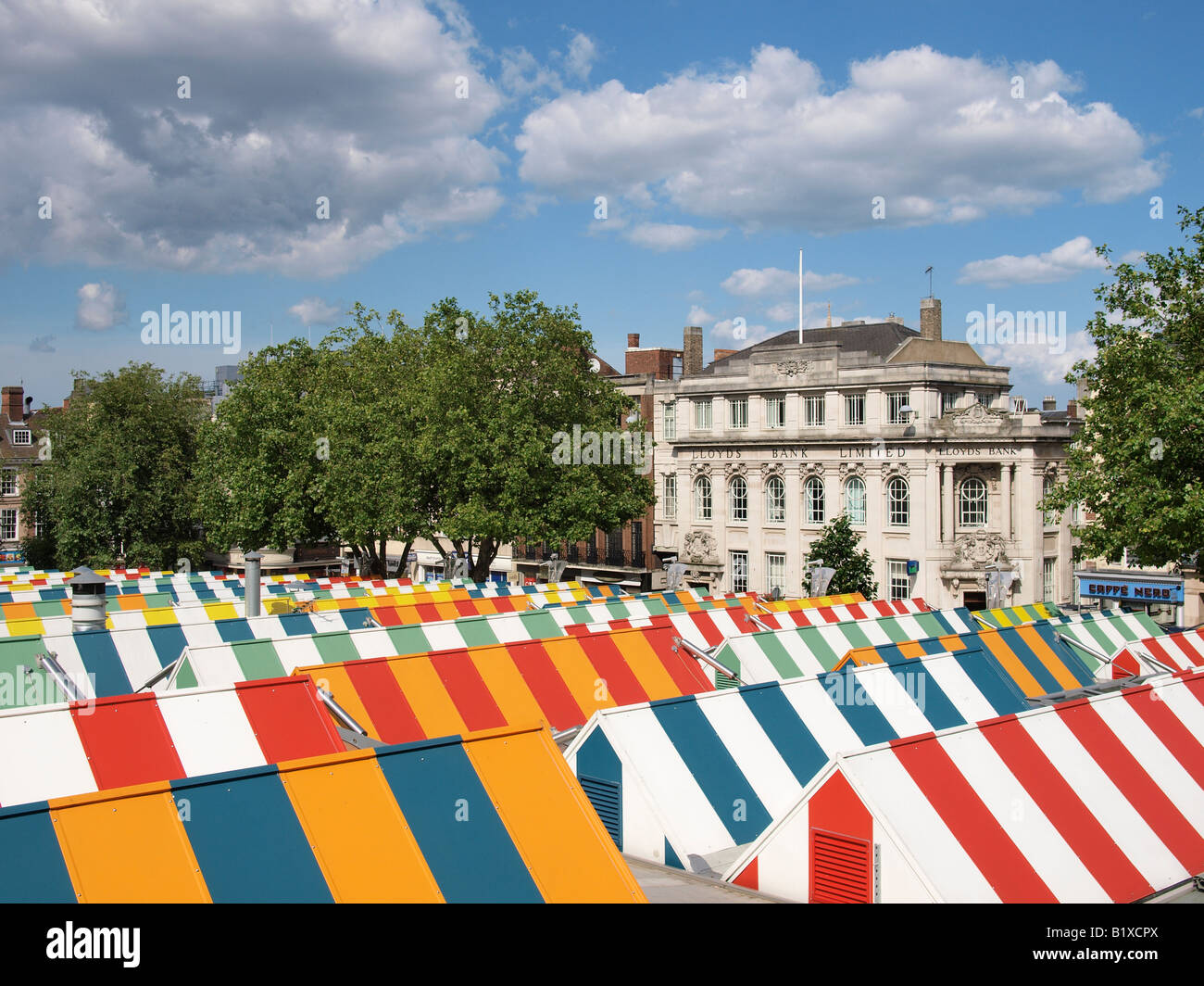 BRIGHTLY COLOURED ROOVES OF STALLS ON NORWICH MARKET WITH LLOYDS BANK ...