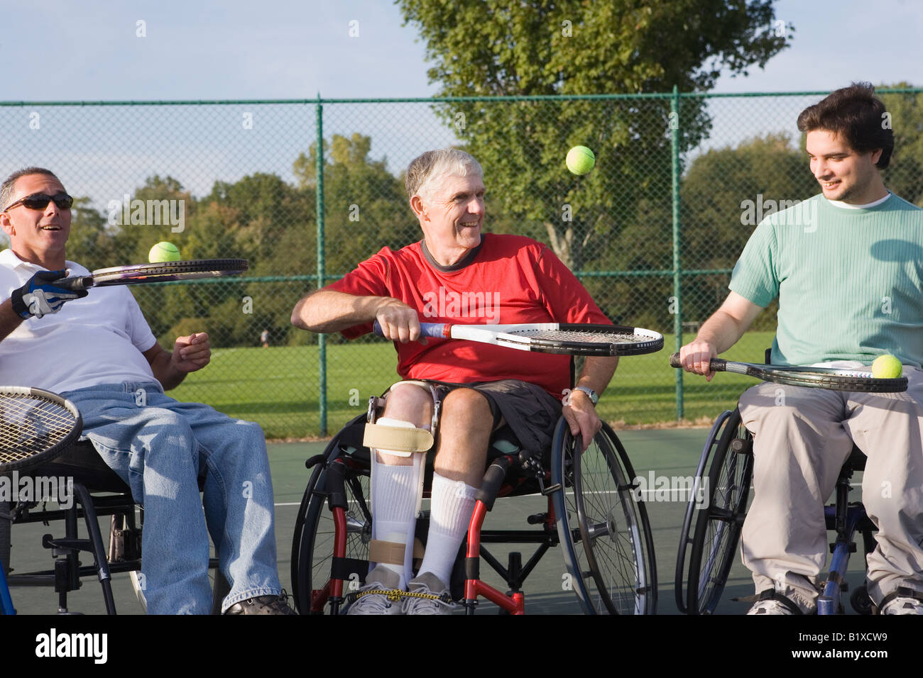 Three handicapped men sitting on wheelchairs and playing tennis Stock ...
