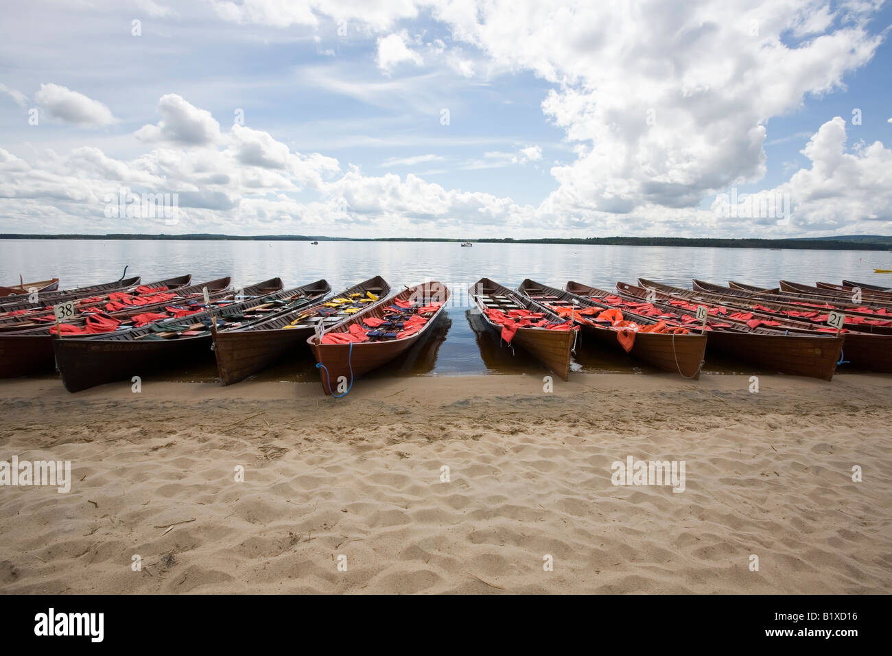 multi-seat wooden row-boats on shore Stock Photo - Alamy