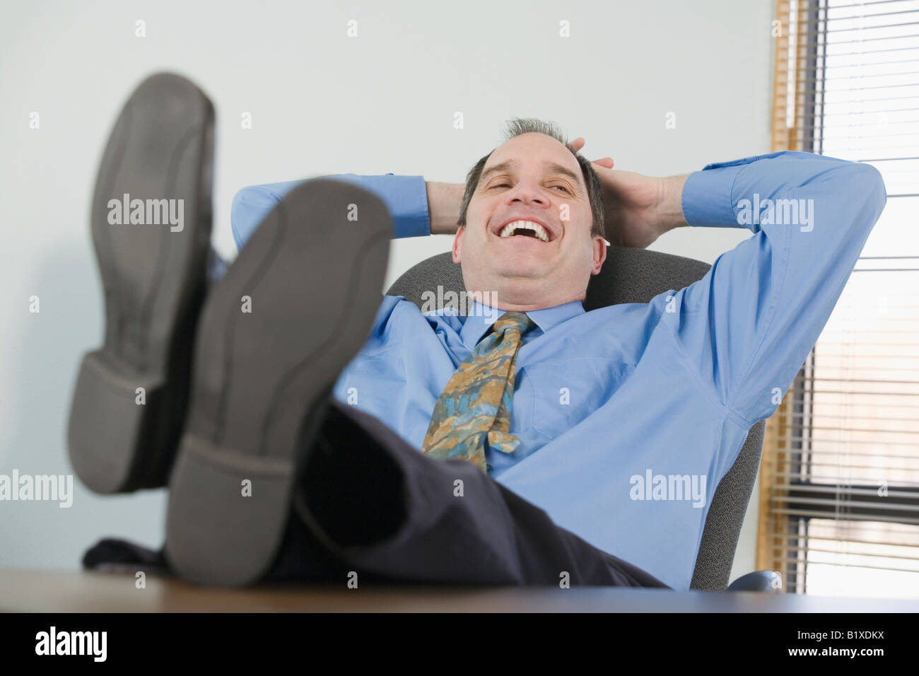 Businessman resting on a chair and smiling Stock Photo - Alamy