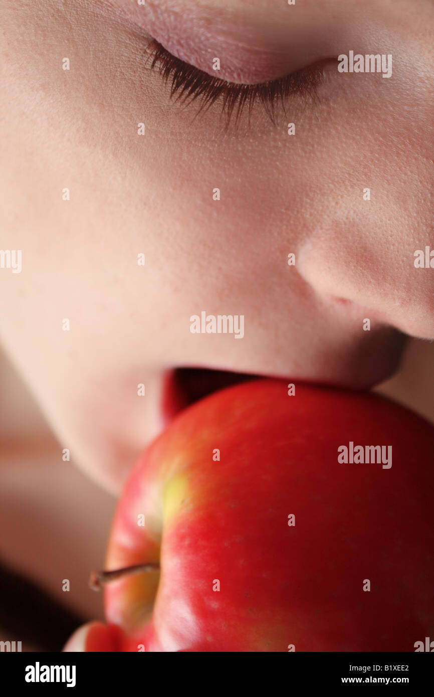 A young female eating a bright red apple Stock Photo - Alamy