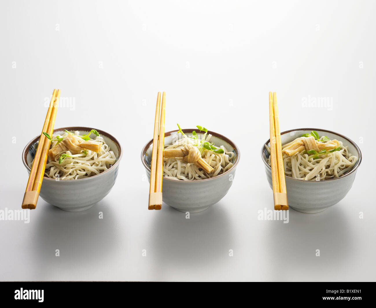 three bowls of noodle with chopsticks on top Stock Photo - Alamy