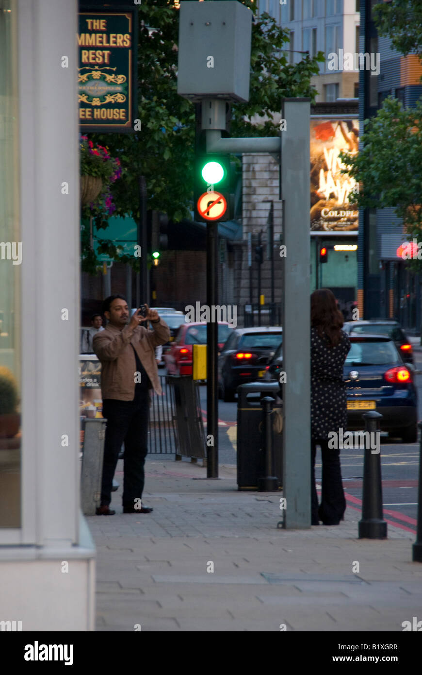 A guy photographs his girlfriend leaning on a traffic light Stock Photo ...