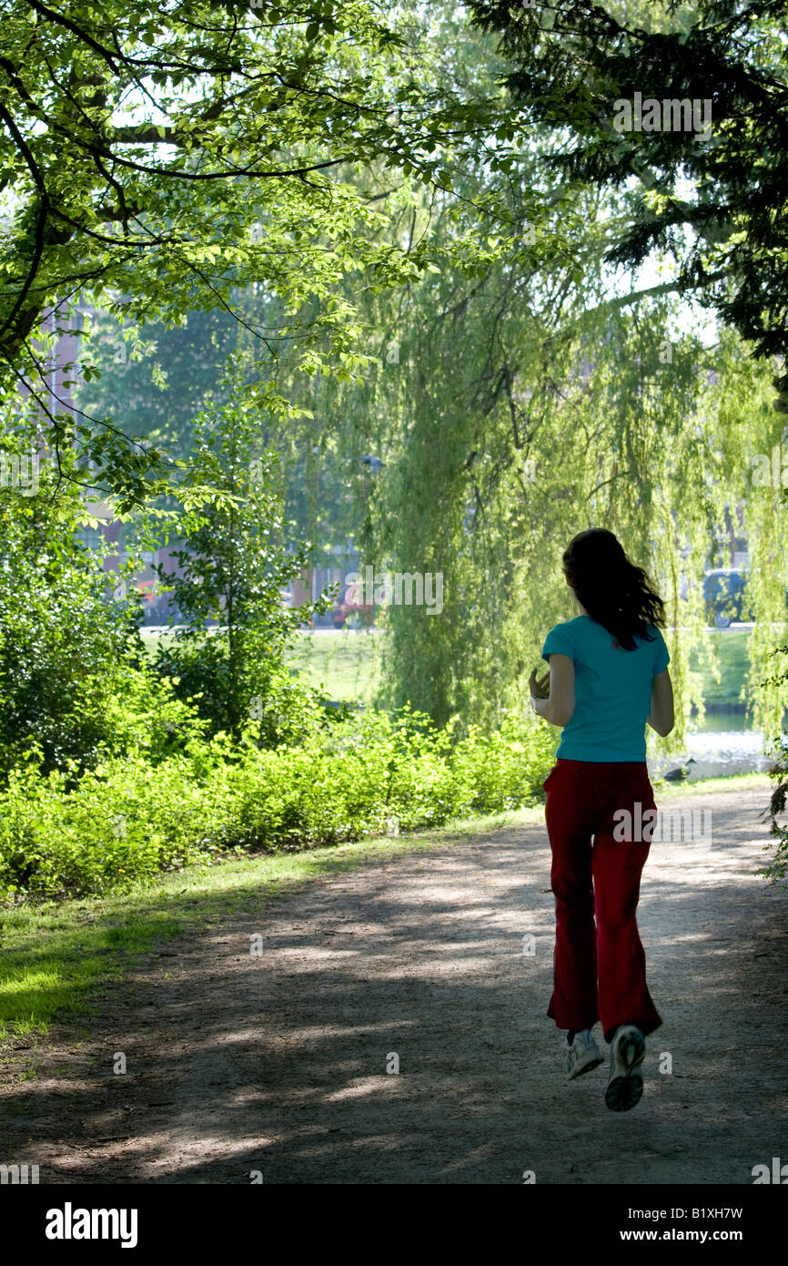 Slim girl running in park under sunlit trees Stock Photo - Alamy