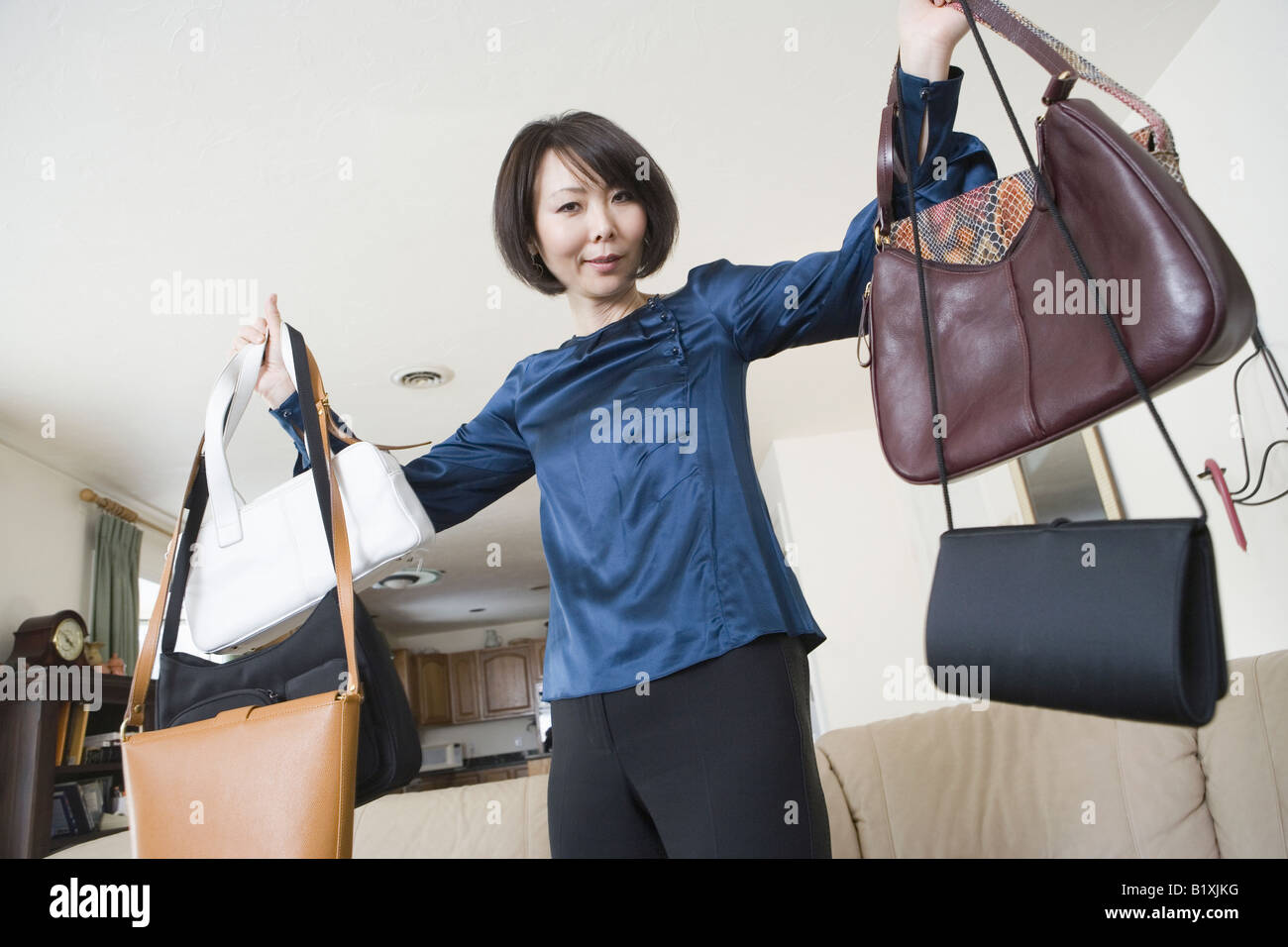 Portrait of a mid adult woman showing off purses Stock Photo - Alamy