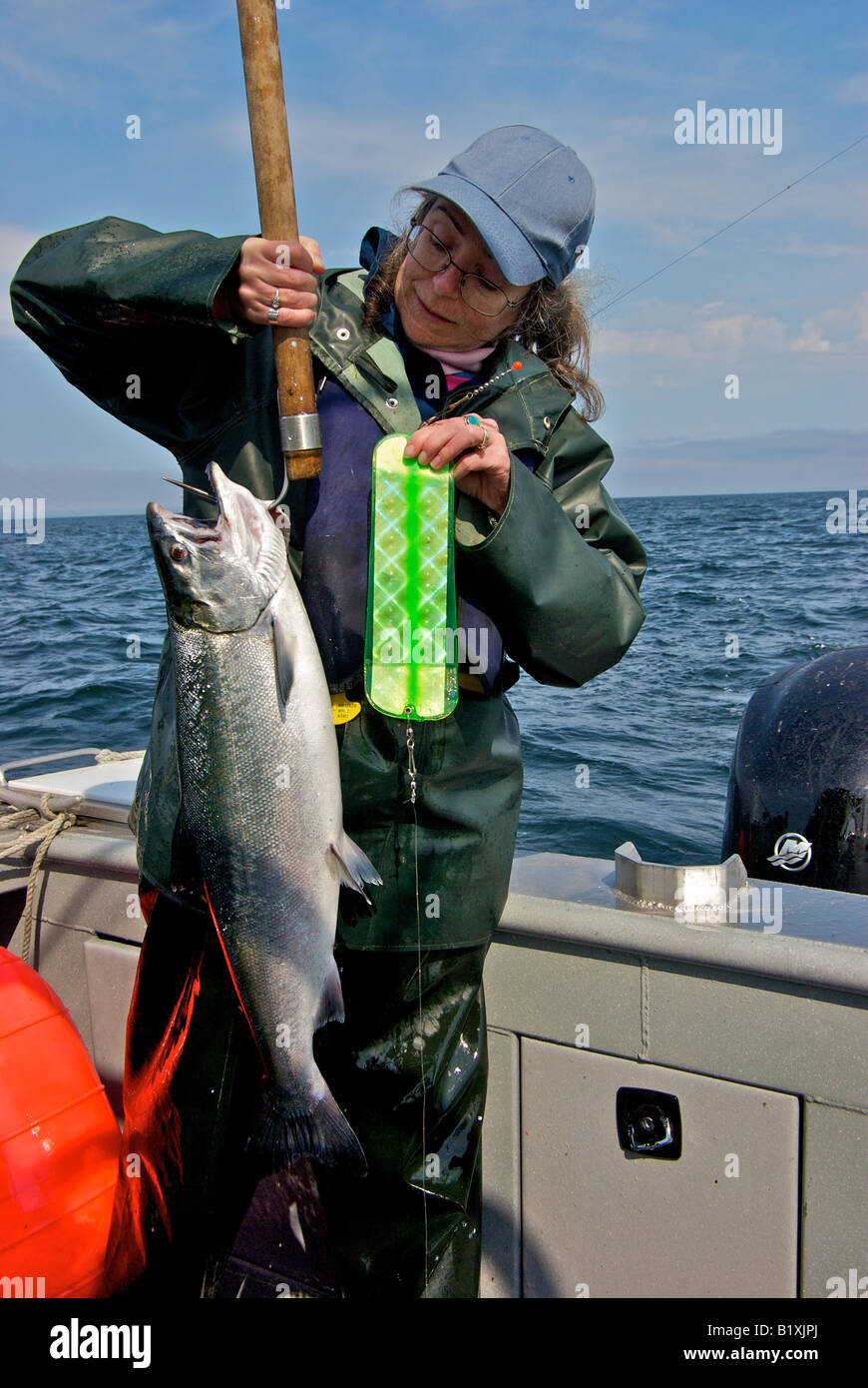 Woman holding a big coho fish on gaff and the green UV glow trolling ...