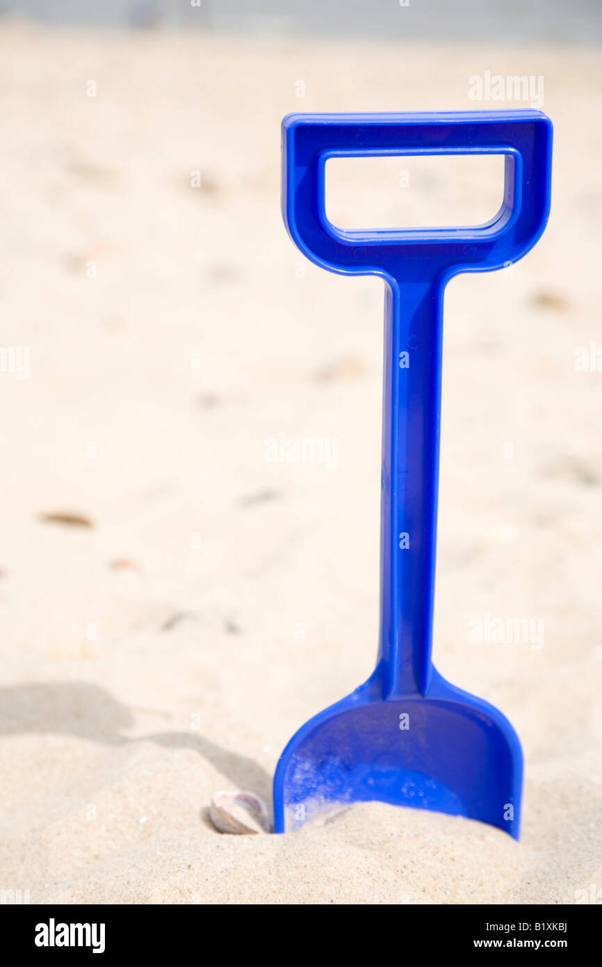 Child's toy blue spade dug into beach sand Stock Photo - Alamy