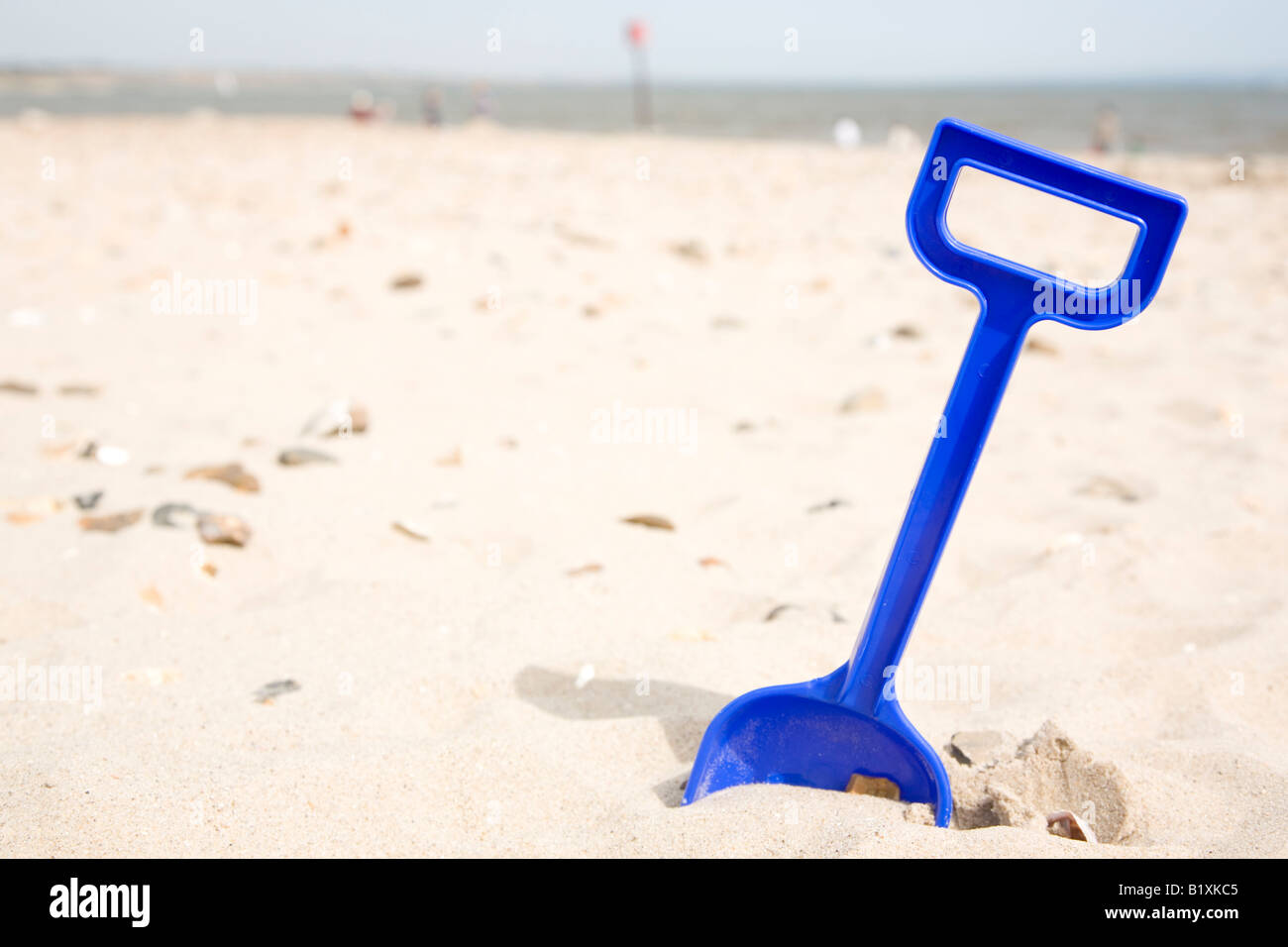 Child s toy blue spade dug into beach sand Stock Photo - Alamy
