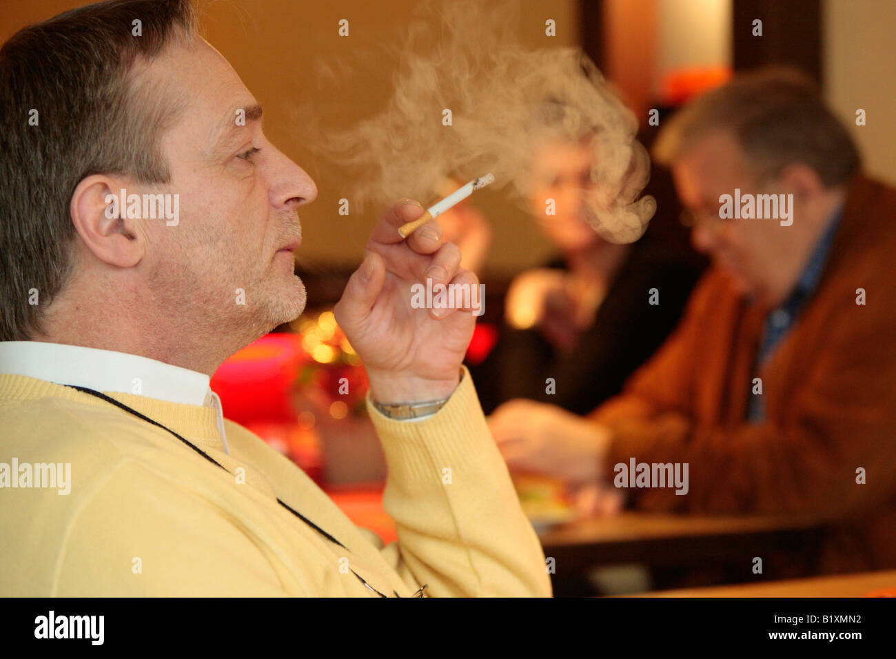 a man smoking a cigarette in a restaurant Stock Photo - Alamy