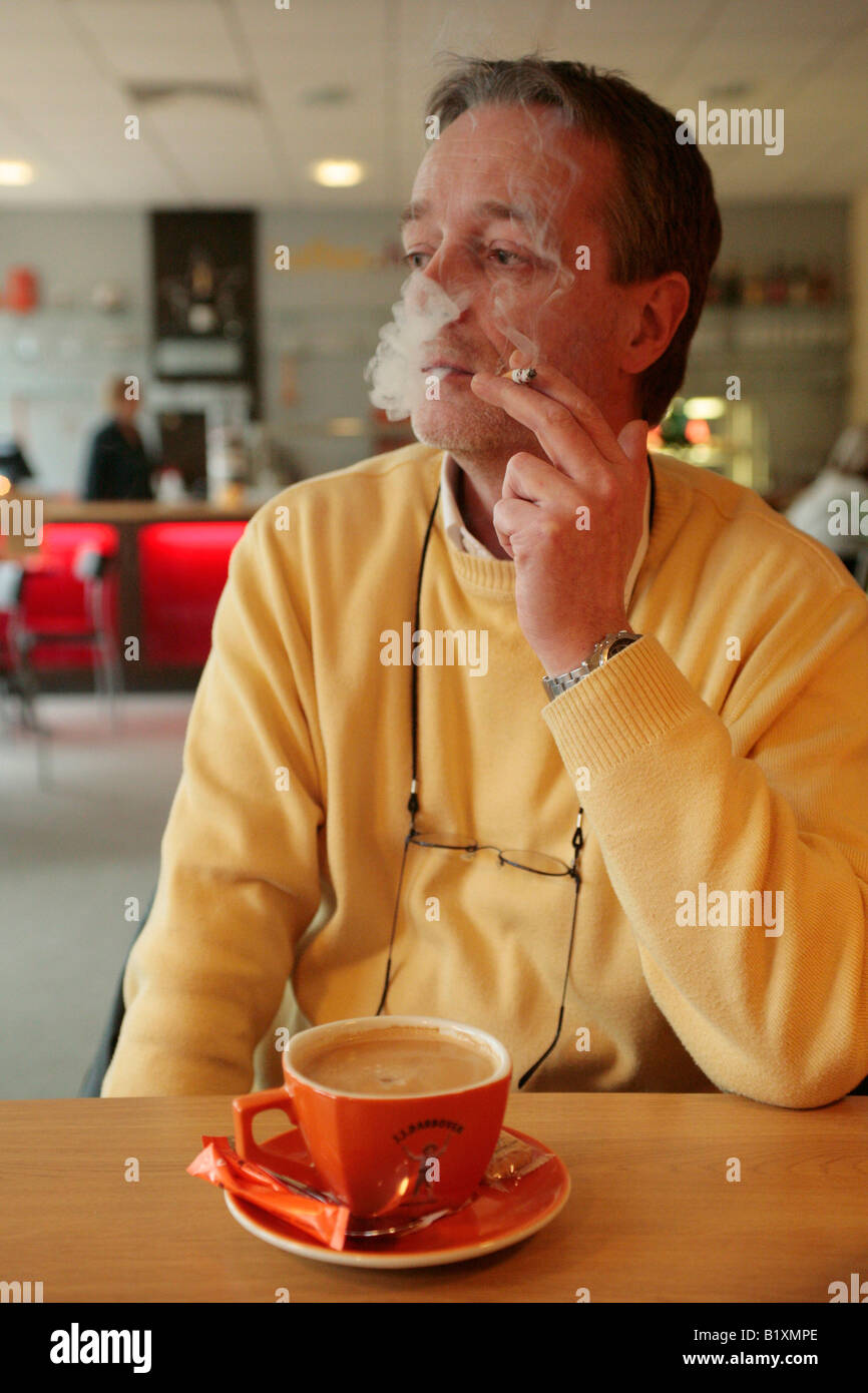 a man smoking a cigarette in a restaurant Stock Photo - Alamy