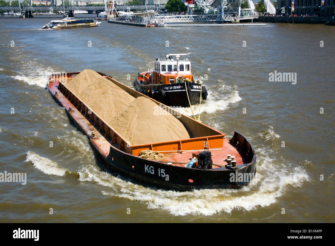 Tug Boat pushes barge full of sand down the river Thames in London ...