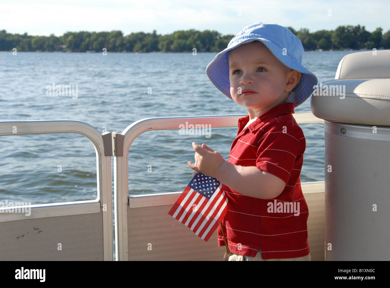 A toddler boy holds an American flag on a boat during the Fourth of ...