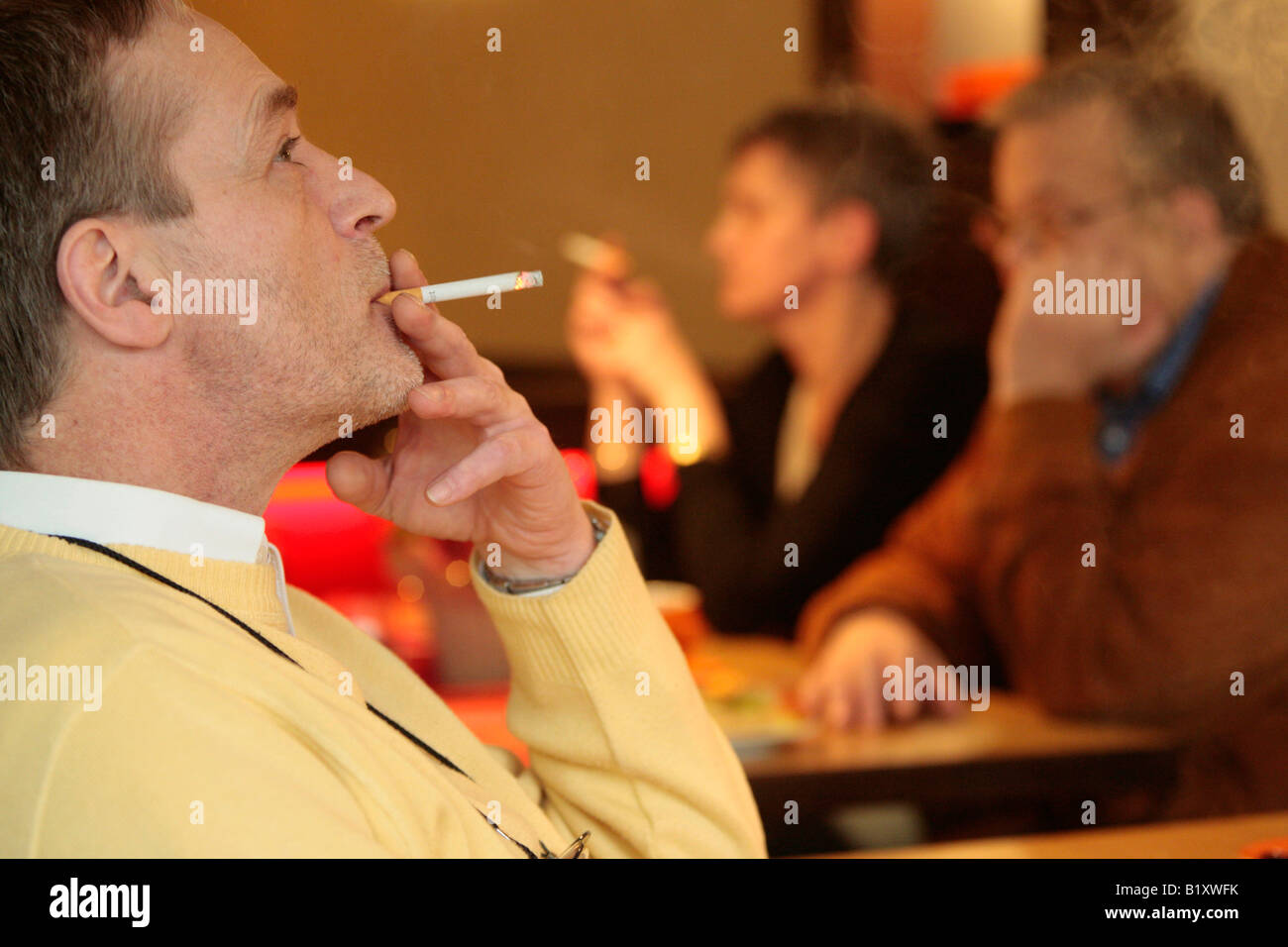 a man smoking a cigarette in a restaurant Stock Photo - Alamy