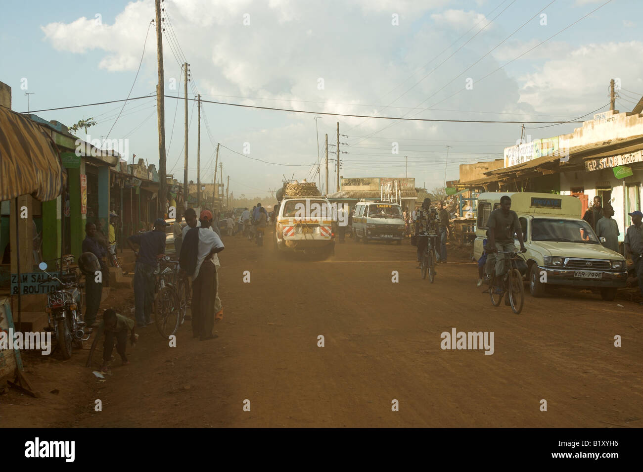 Dusty street scene with cars and people on bicyles Mumias Kenya Africa ...
