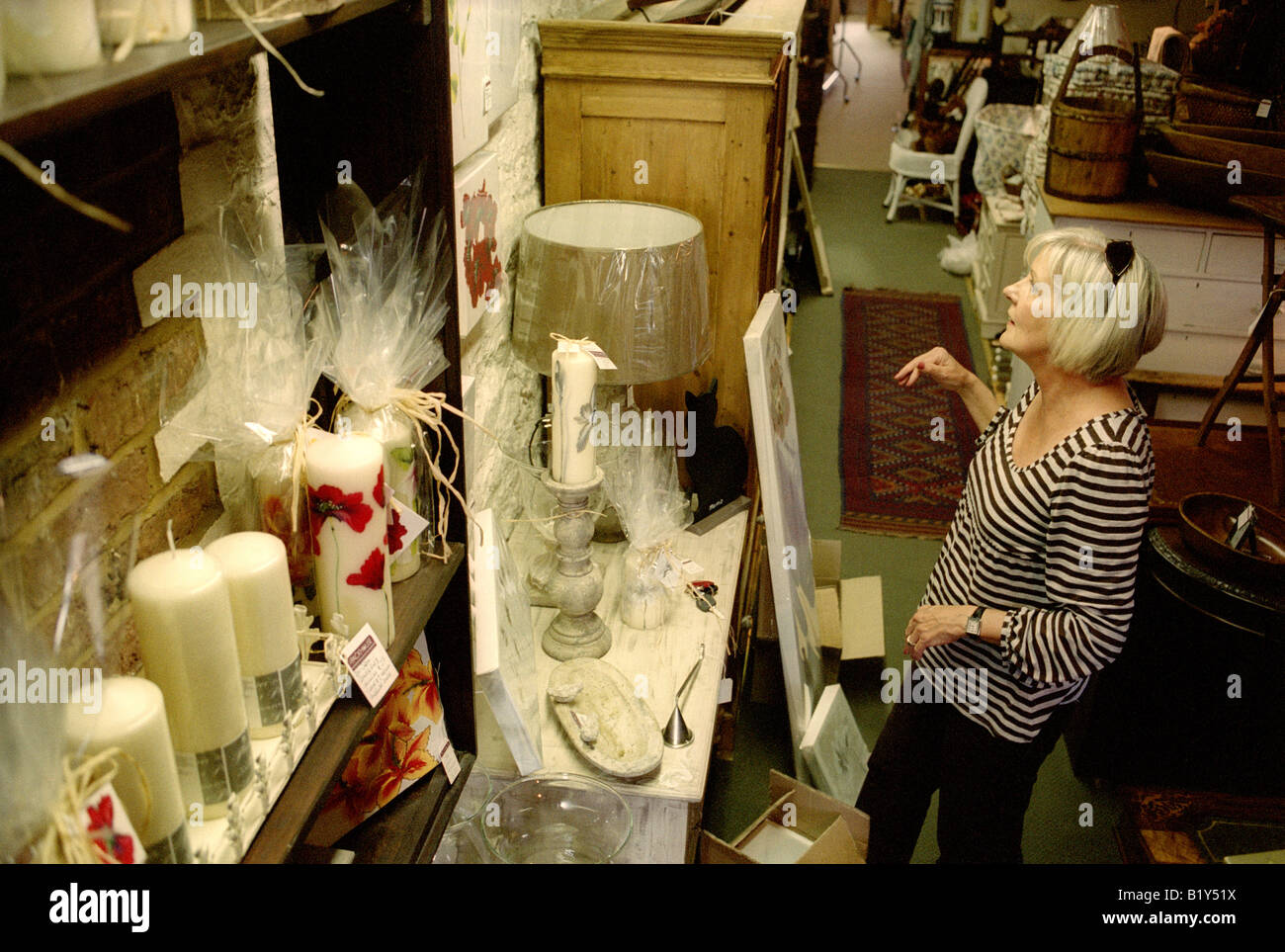 Woman viewing objects at an indoor antiques and interior design market ...