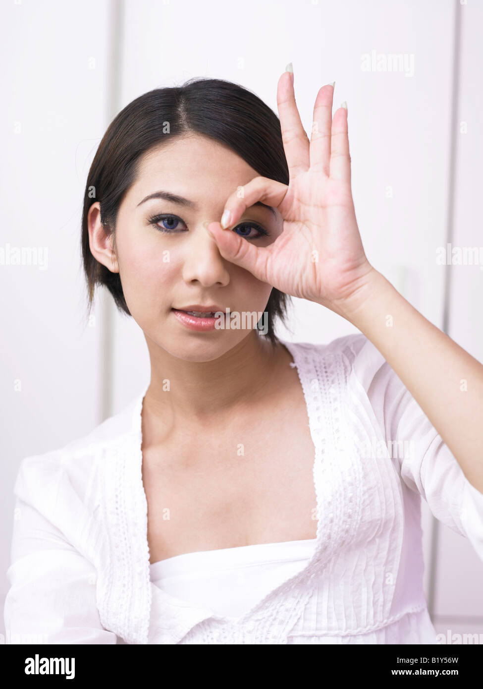 Pretty young lady with hand sign on face Stock Photo - Alamy