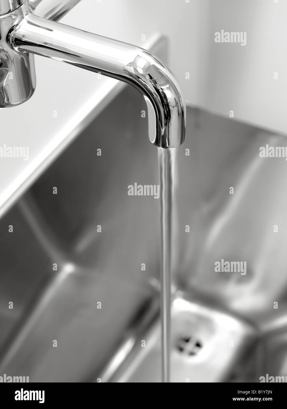 Running chrome water tap into sink Stock Photo - Alamy