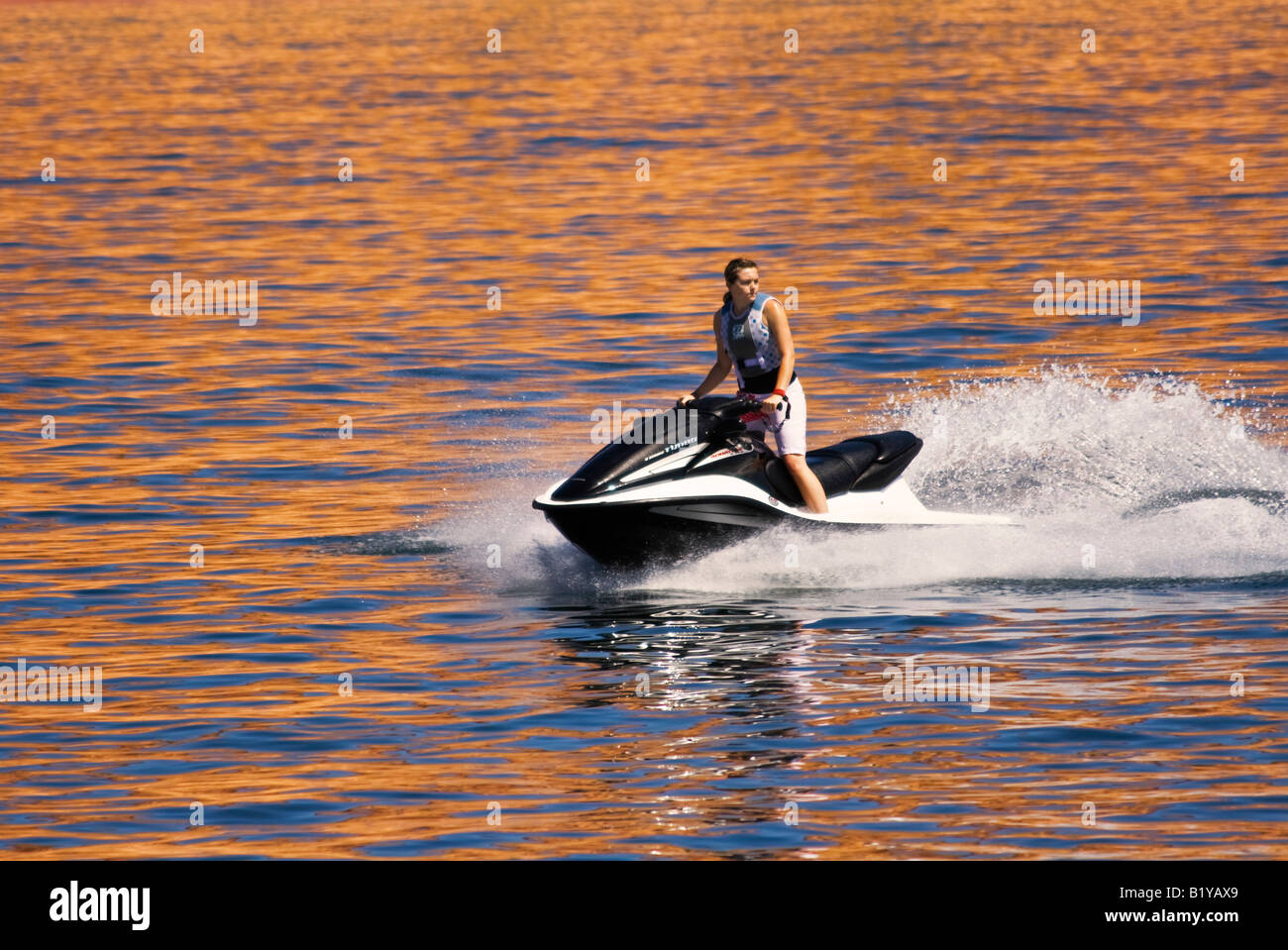 Young woman riding jet ski and sunset reflecting on the water Stock ...
