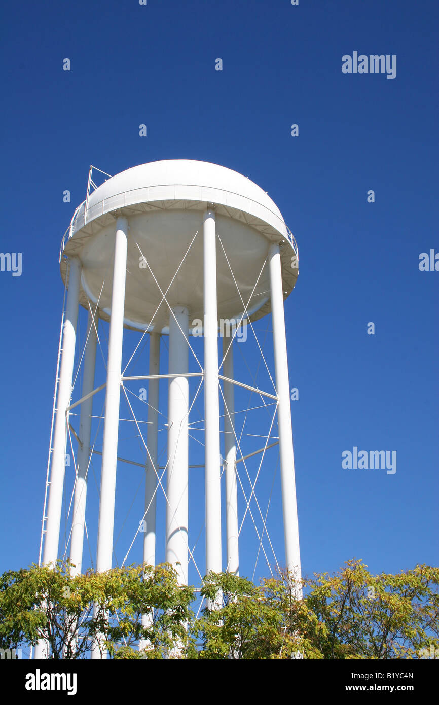 White water tower rising from trees against blue sky Stock Photo - Alamy