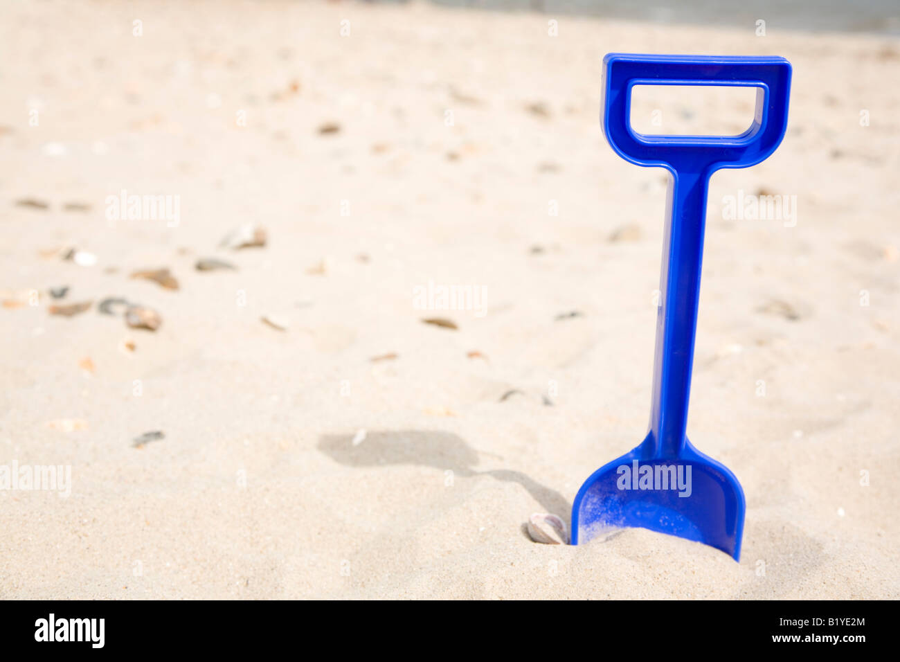 Child's toy blue spade dug into beach sand Stock Photo - Alamy