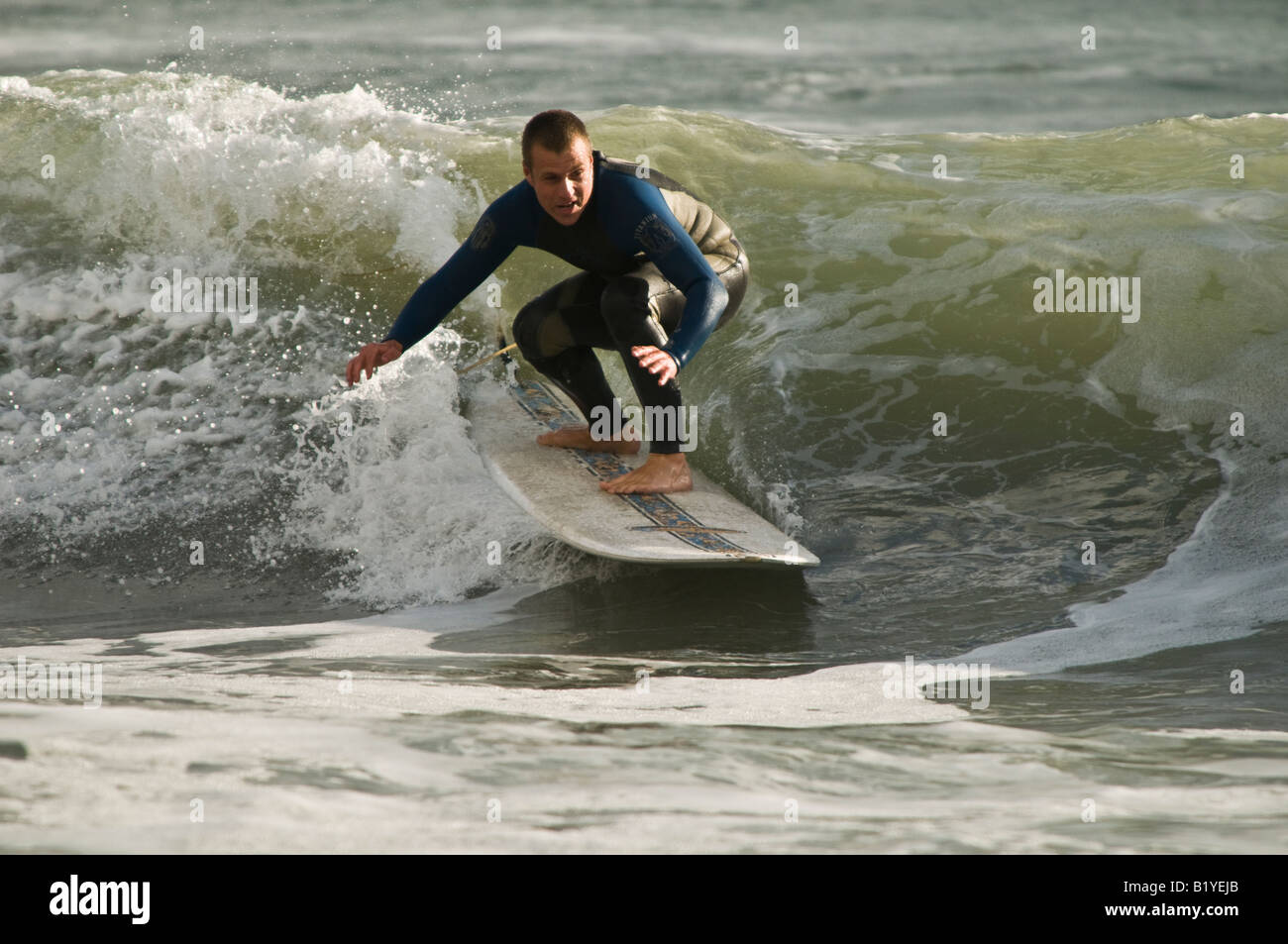 Man wearing wet suit on surfboard surfing waves at Borth Cardigan Bay ...