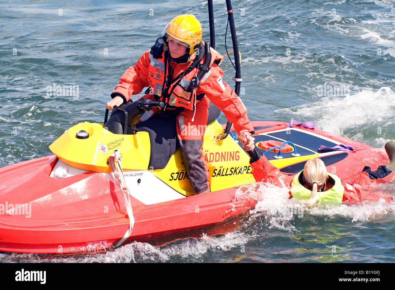 Sea Rescue boatman helps distressed person to get aboard a rescuerunner ...