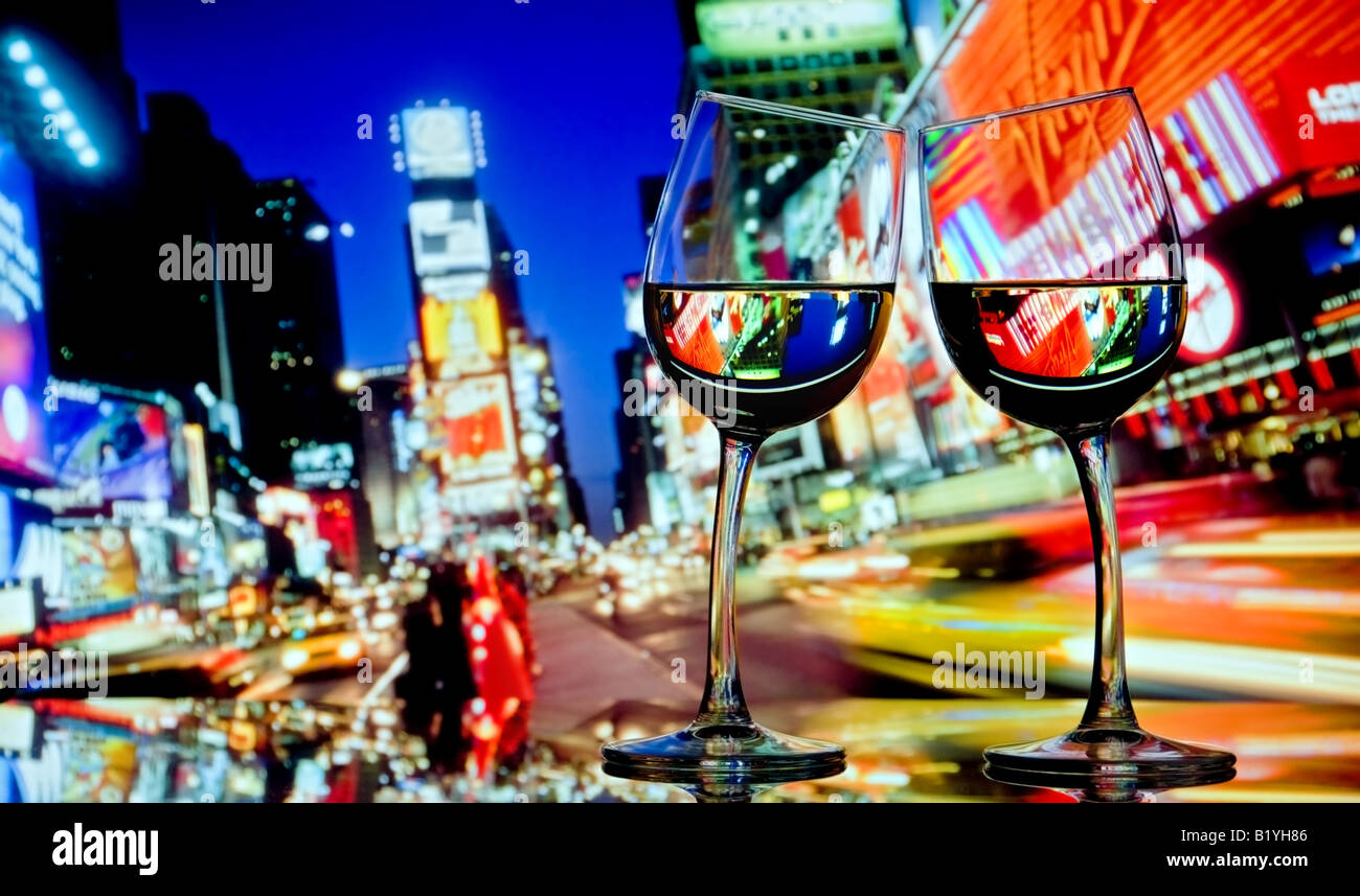Two white wine glasses lean towards each other with a busy Times Square ...