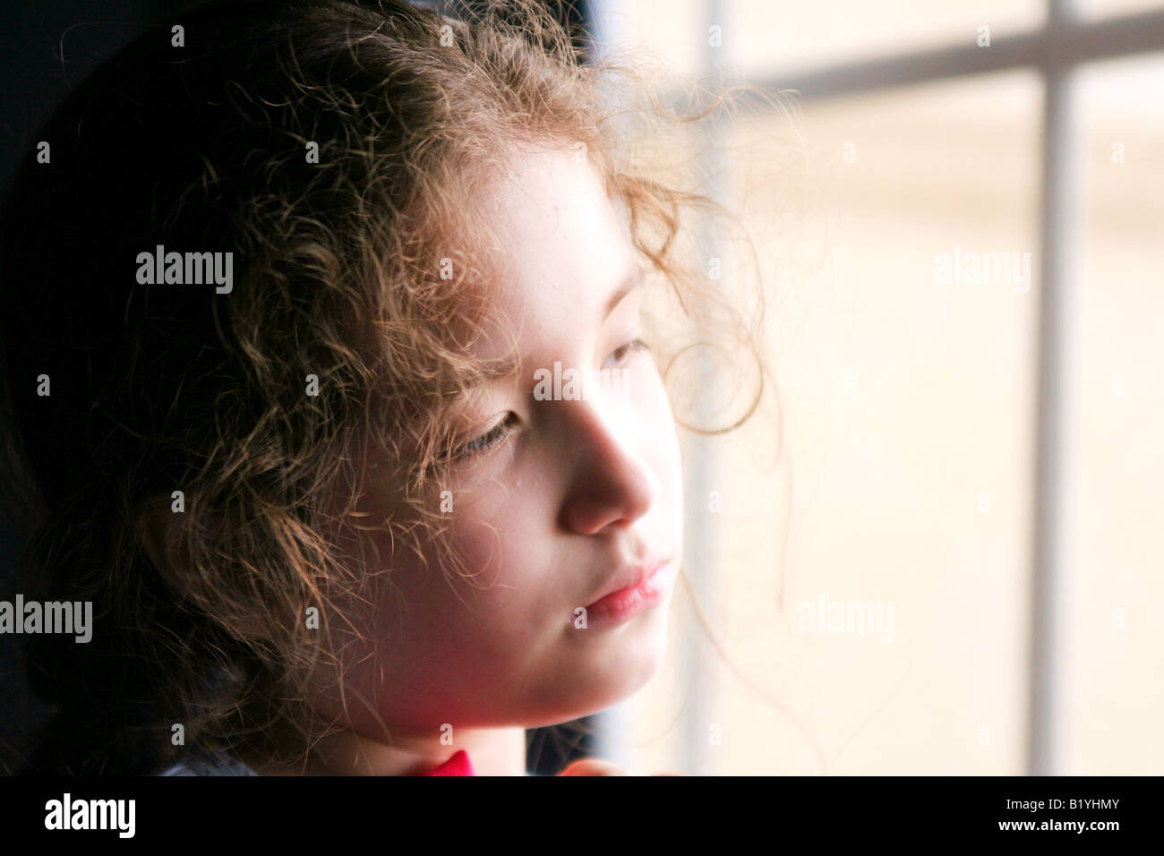 Pretty young girl melancholic staring outside the window Stock Photo ...