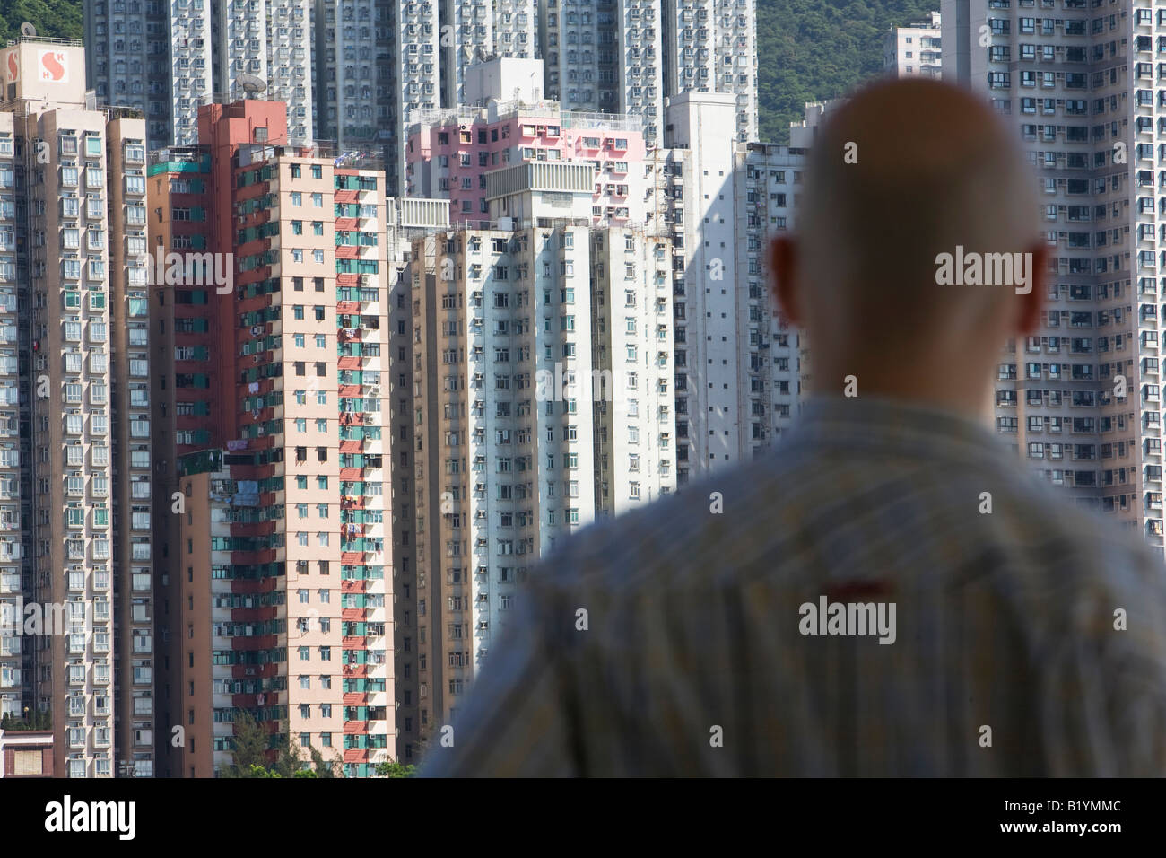 A man stares out at Hong Kong residential buildings in the distance ...
