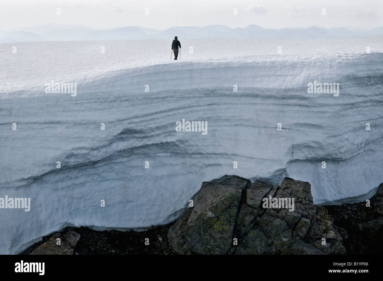 Silhouette of hiker above large snow cornice at summit of Ben Nevis ...