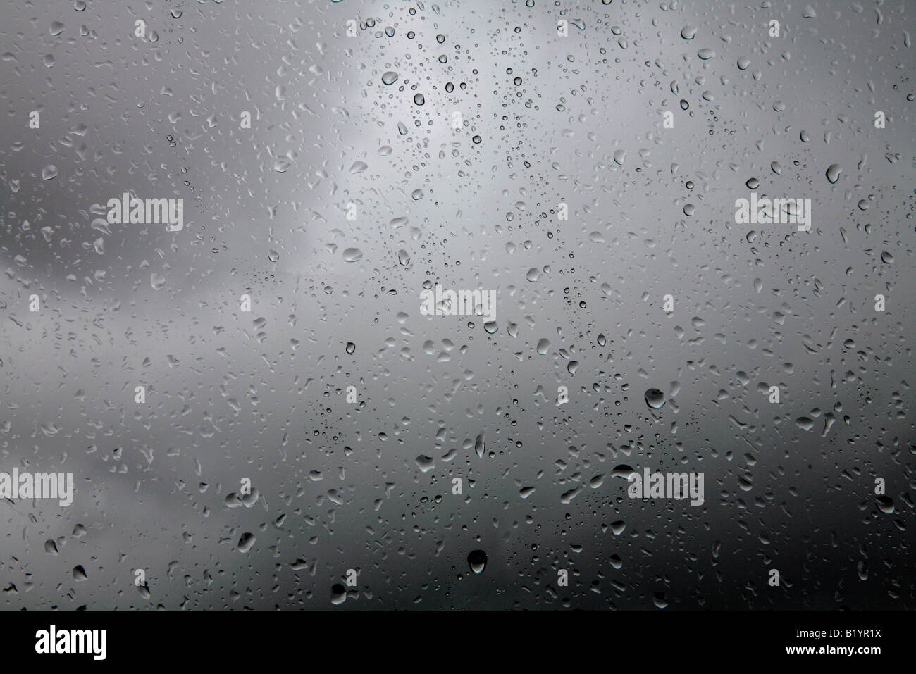 Rain Drops on window pane with dark moody clouds in background Stock Photo - Alamy