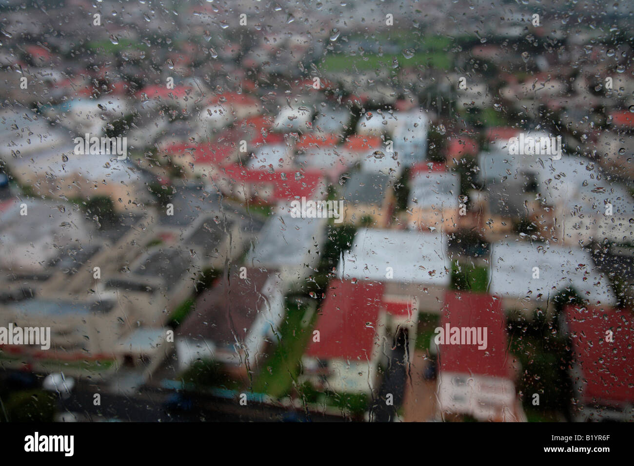 Rain drops runnung down window pane with out of focus buildings in ...