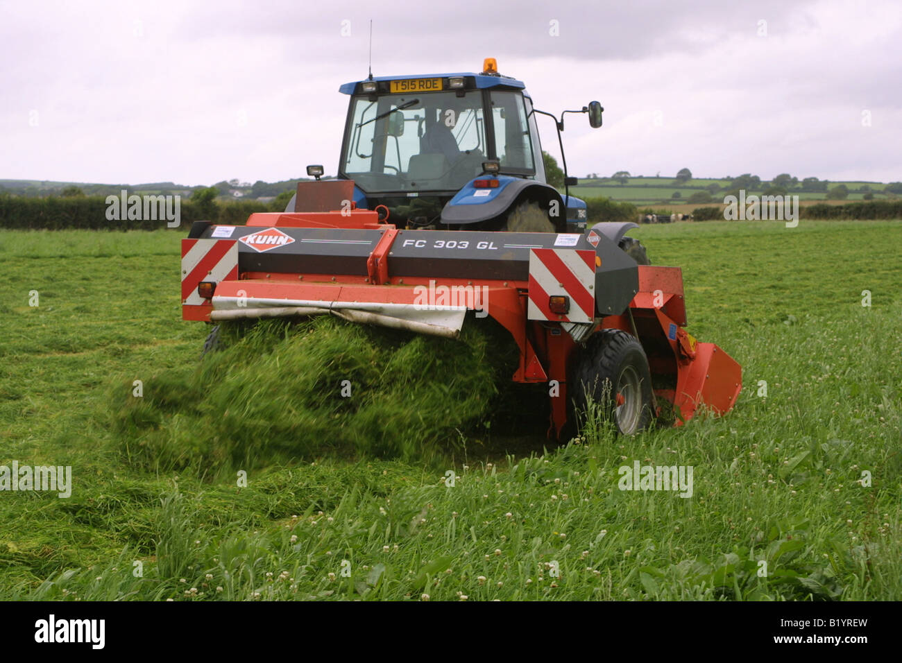 Tractor and red farm machinery cutting grass for silage.Horizontal ...