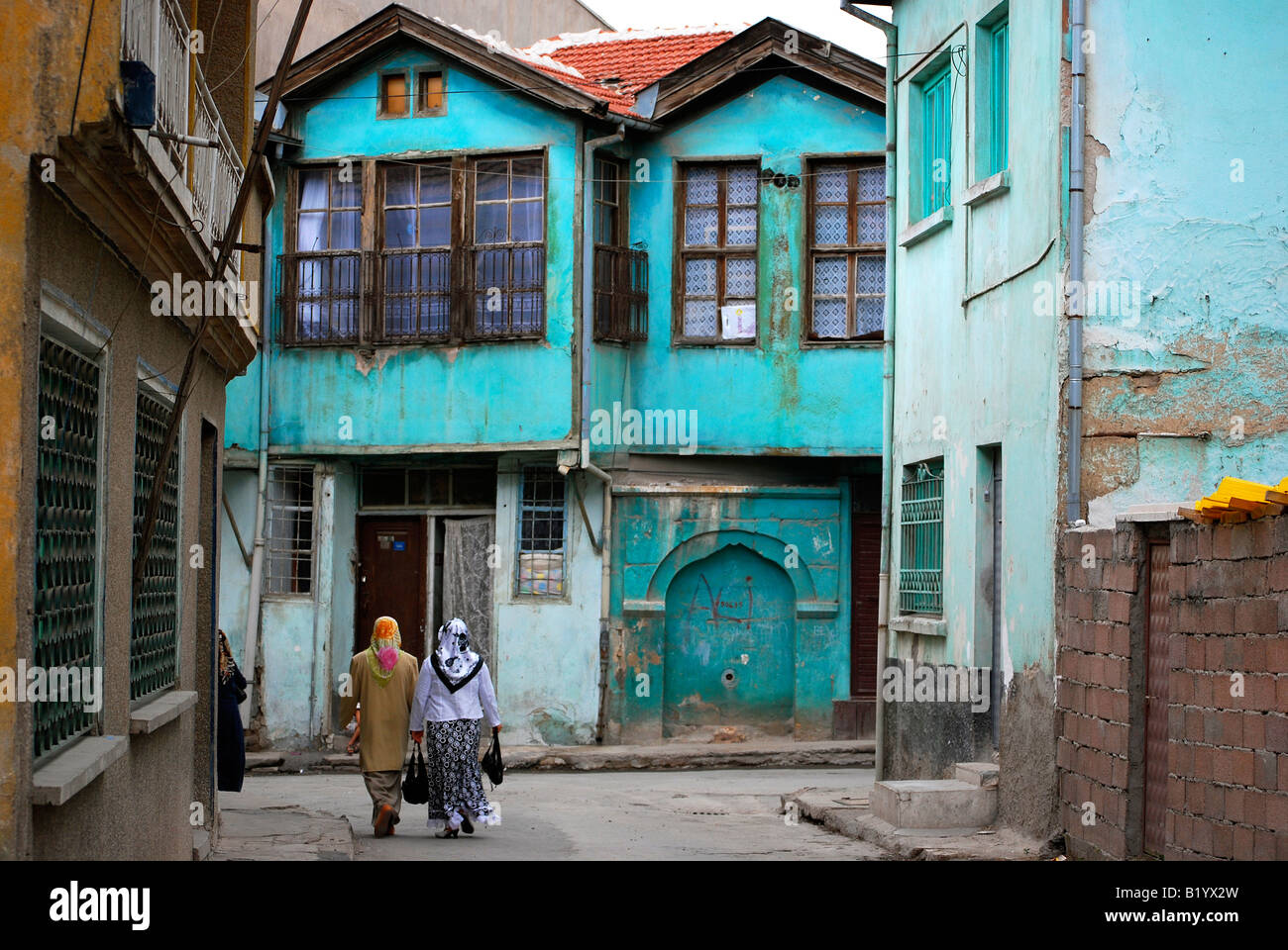 Two scarf-clad women walk down a street lined with traditional wooden ...