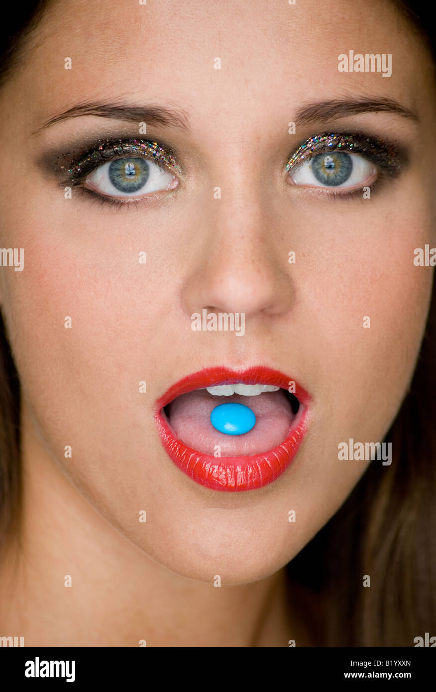 woman with a blue pill or sweet on her tongue Stock Photo - Alamy