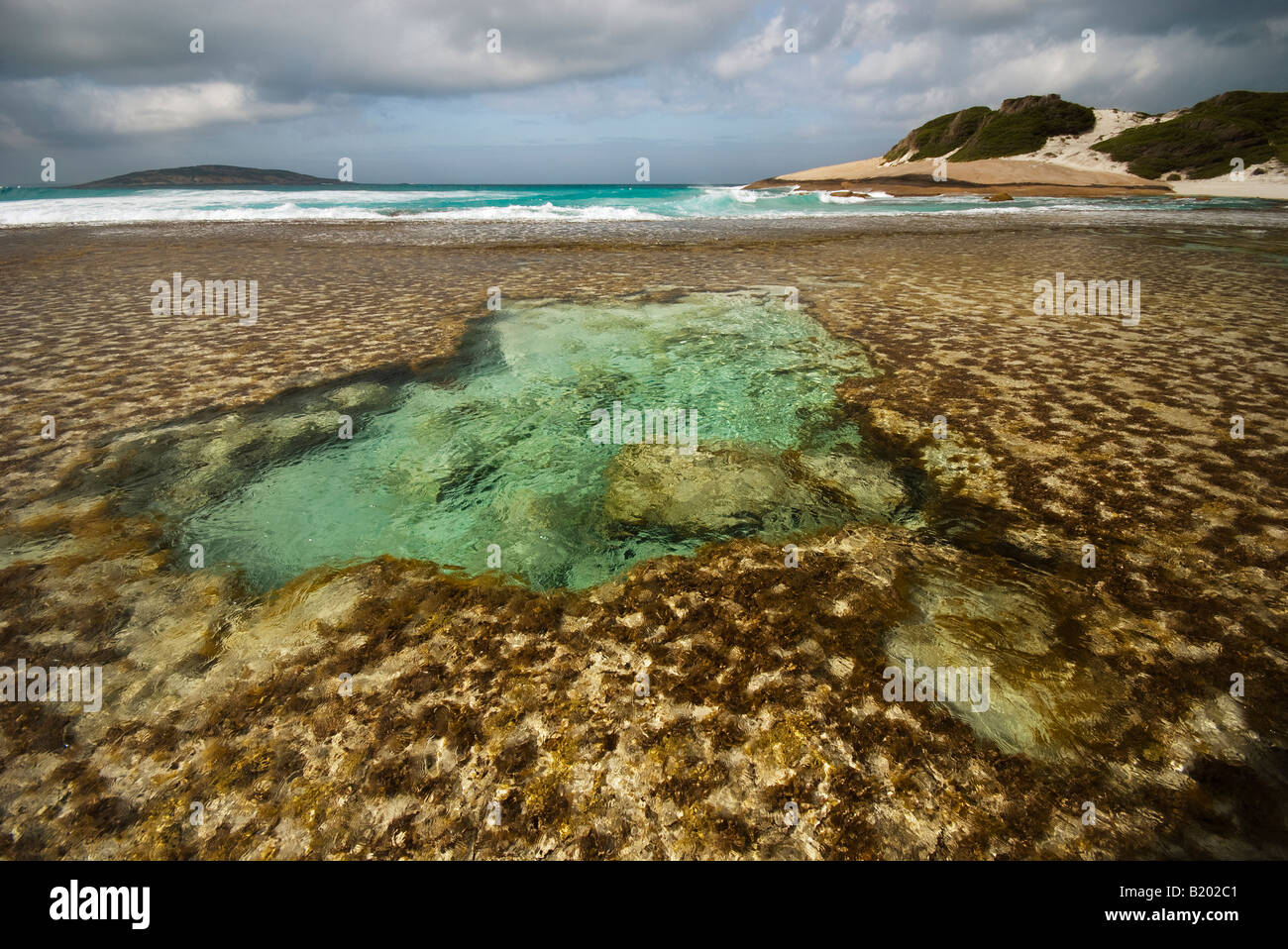 A small clear rock pool with an approaching storm in the background ...