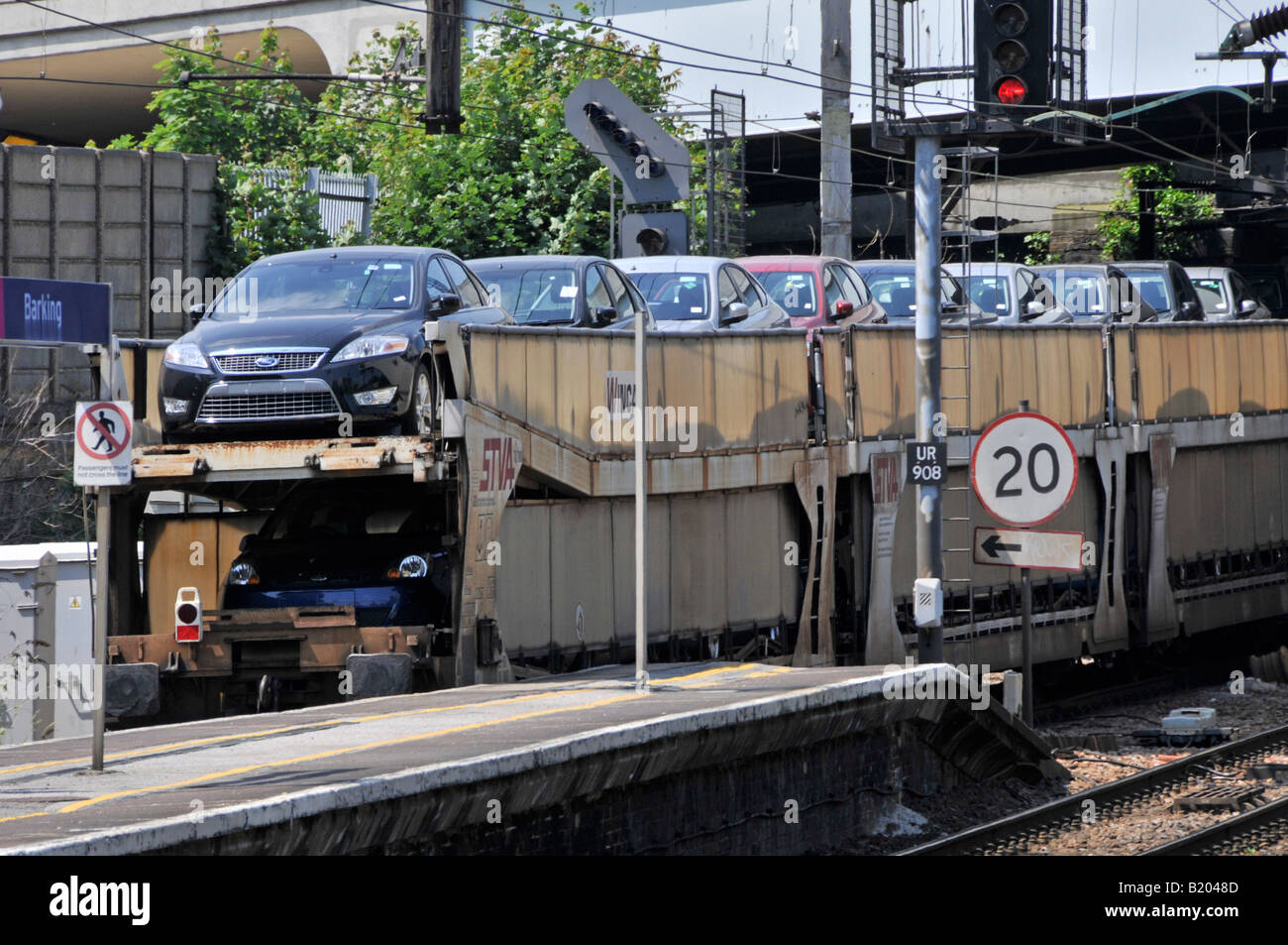 Freight train loaded with new cars from factory passing through station ...