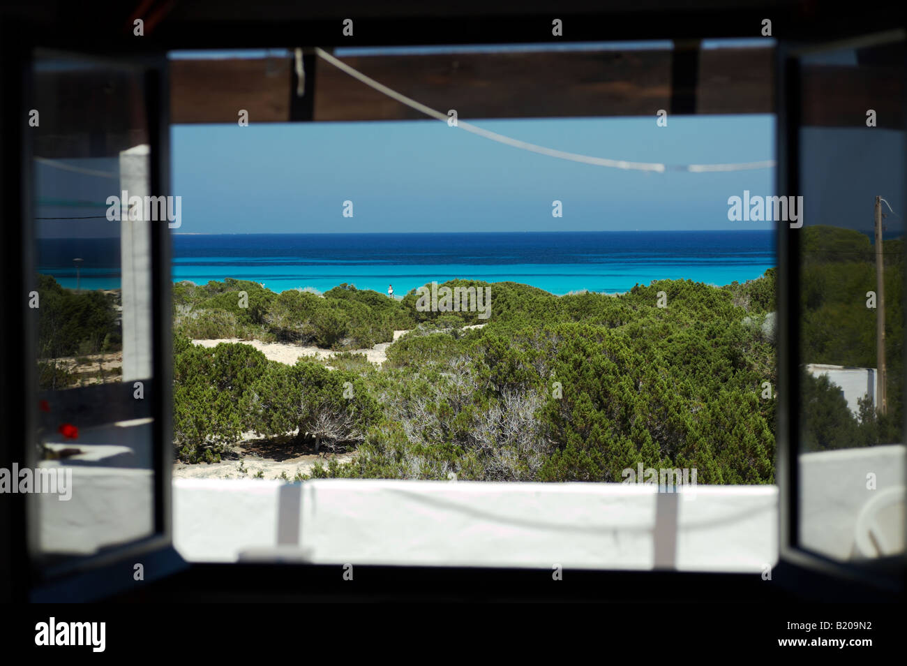 Apartment window view over sand dunes to a bright turquoise blue ...