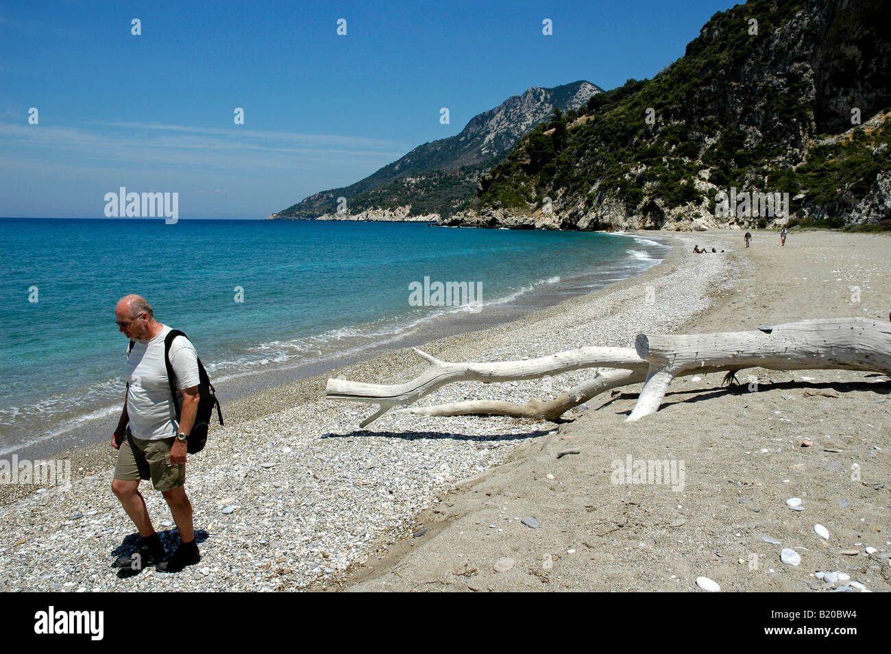 A lonesome wanderer walks on the pebbles of the Megalo Seitani Beach in ...
