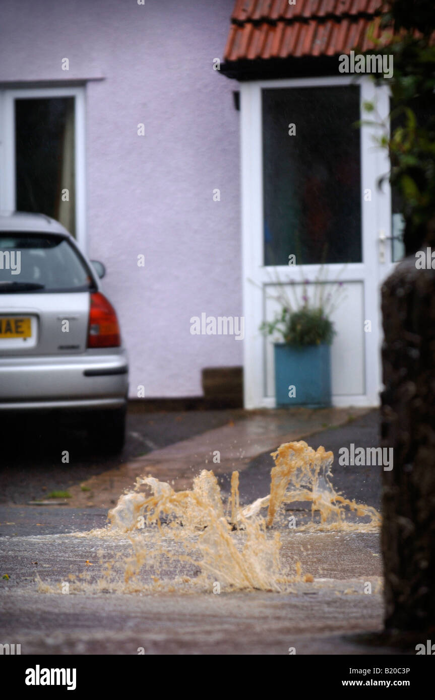 RAIN WATER SPURTS OUT OF DRAINS IN A RESIDENTIAL STREET DURING THE ...
