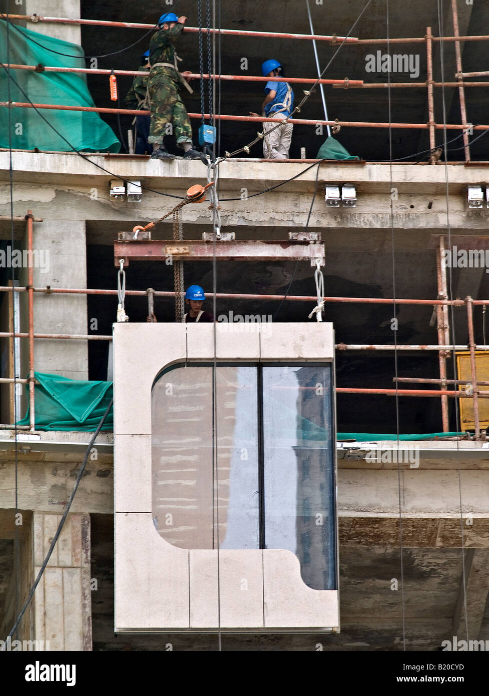 Building a New Shanghai - construction workers lift giant window ...