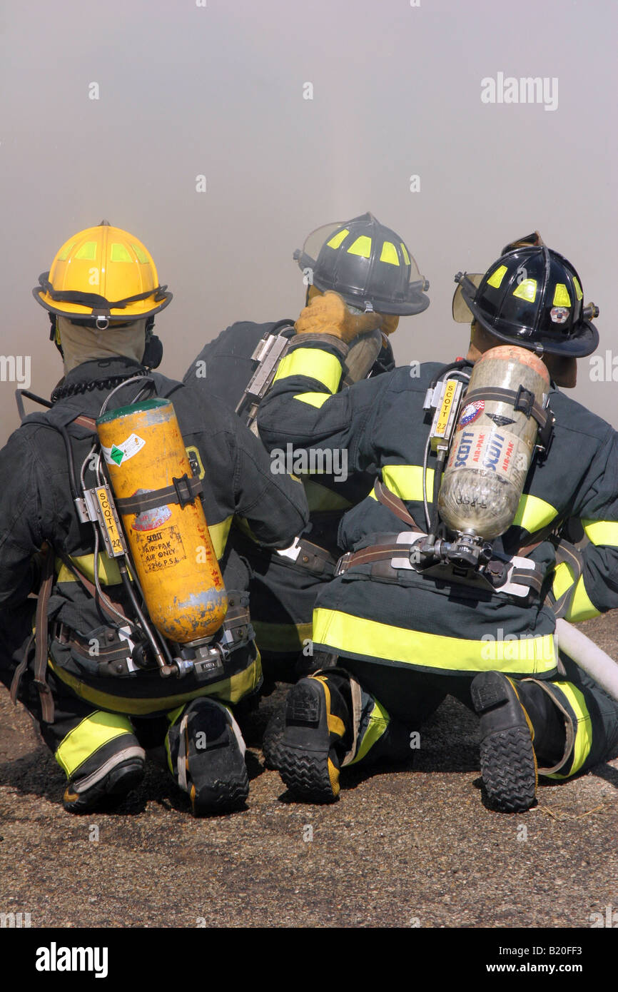 Three fire fighters putting out a fire Stock Photo - Alamy